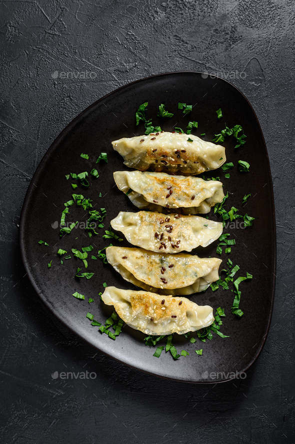 Plate of fried Korean dumplings on rustic black table. Dim sum on a ...