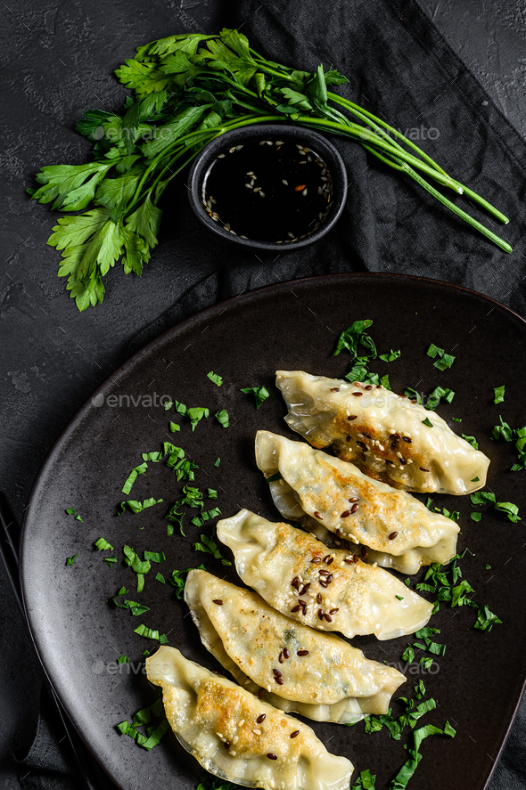 Plate of fried Korean dumplings on rustic black table. Dim sum on a ...