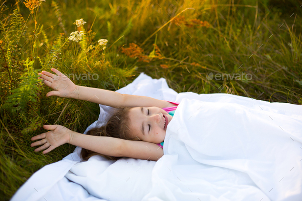 Girl sleeps on bed in grass, Sweet stretches and yawns sleepily Stock ...