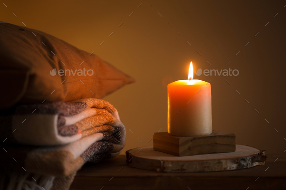 candle and stack of wool textile fluffy plaid blankets in interior ...
