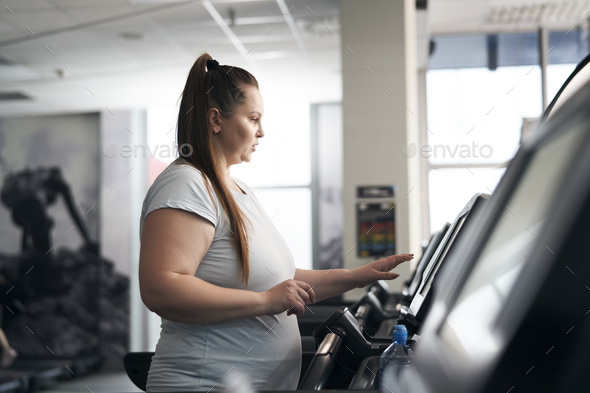 Plus size caucasian woman running on treadmill at gym Stock Photo by ...