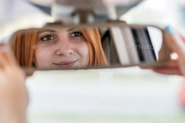 Young woman driver checking rear view mirror looking backwards while ...