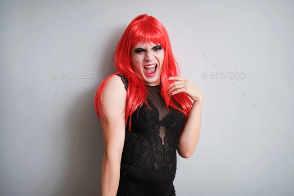 Portrait of drag queen screaming and wearing a red wig on grey ...