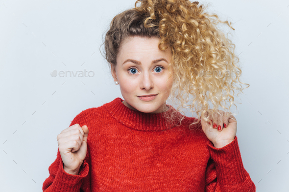 Horizontal shot of beautiful blue eyed funny female with curly bushy ...