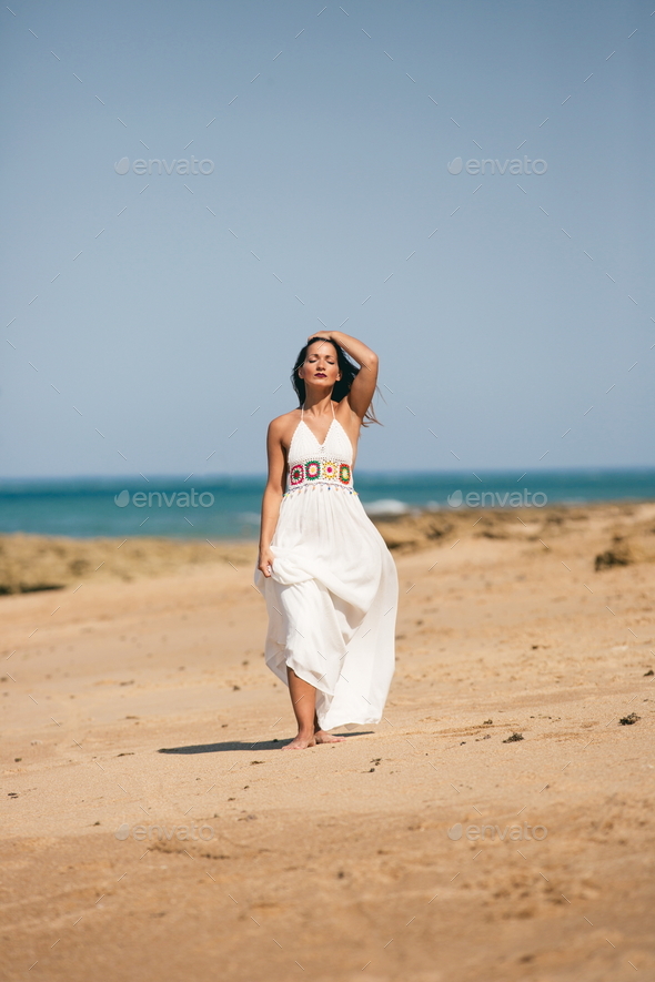 Woman in white dress walking head-on on the beach sand Stock Photo by ...