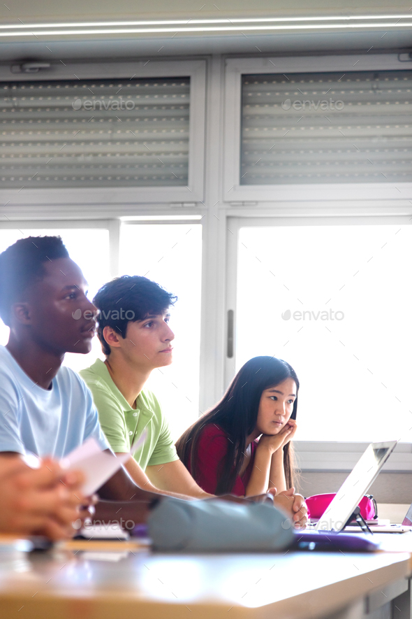 Asian female teen college student in class with multiracial classmates ...