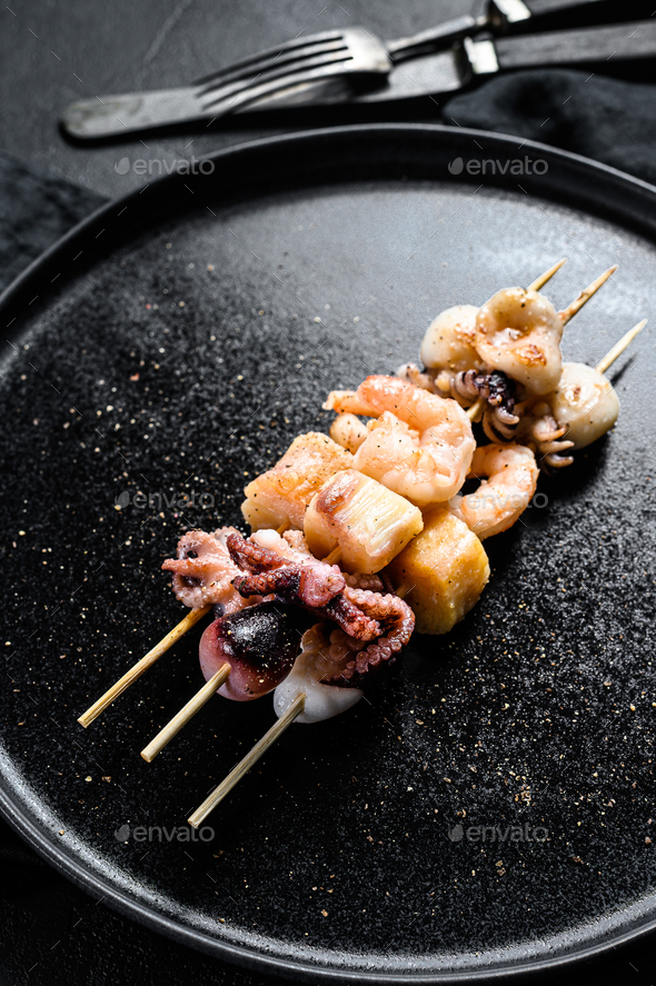 Wooden skewers with shrimp, octopus, squid and mussels. Kebab with ...