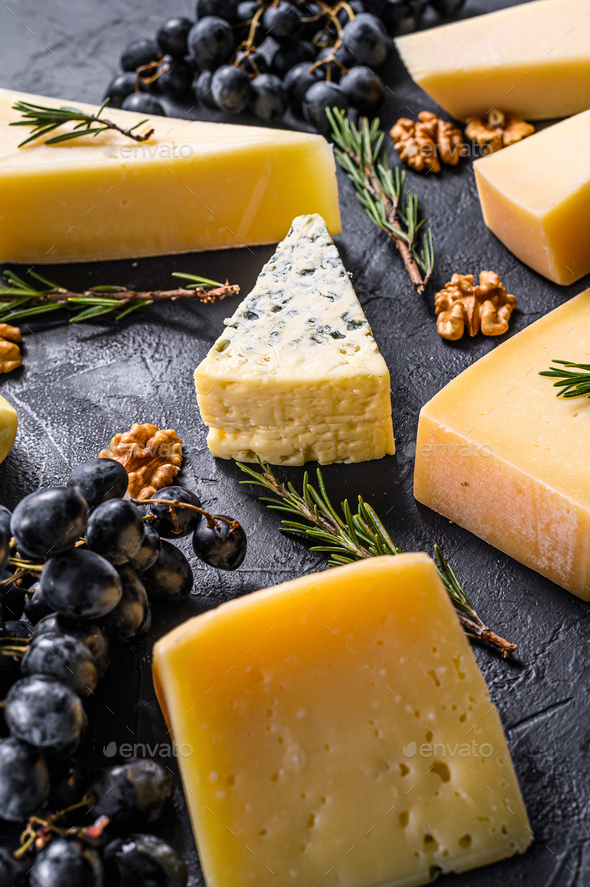 Different types of delicious cheese with walnuts and grapes. Black ...