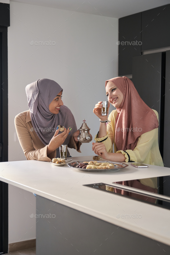Two muslim women talking, drinking tea and eating arabic sweets. Stock ...