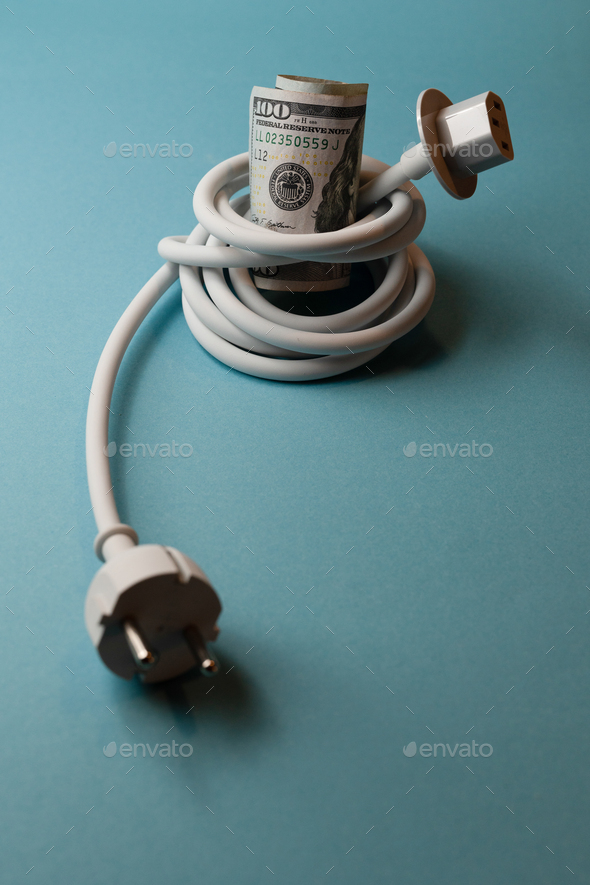 Electric plug and dollar bills on blue background. Stock Photo by Pasanheco
