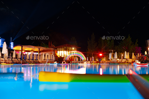 Swimming pool at a luxury resort at night time Stock Photo by FabrikaPhoto