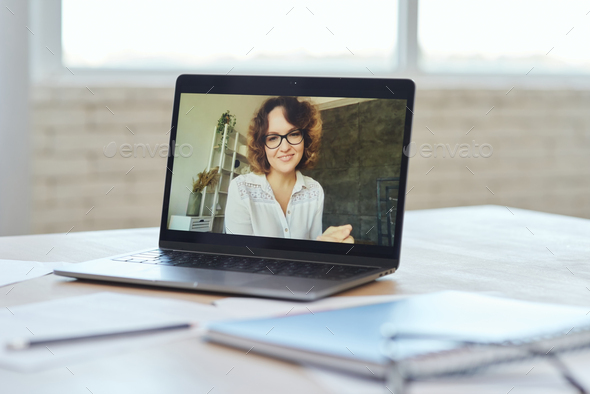 Female teacher smiling at camera during video call while having online ...
