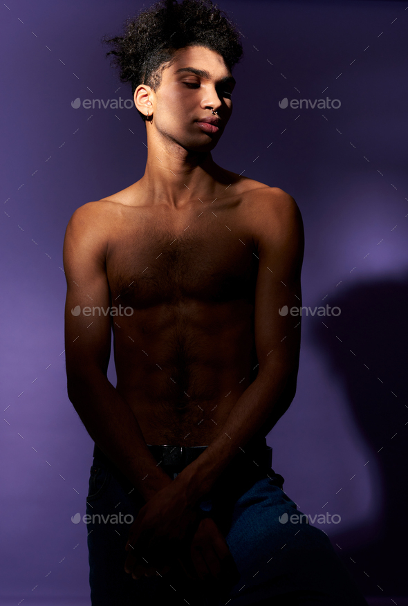 Verticale portrait of young man standing in casual pose in shadow ...