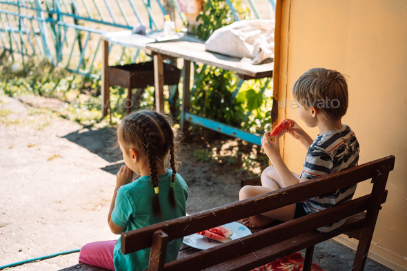 Children sitting on a bench eat watermelon Stock Photo by Nestea06