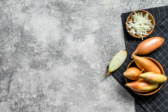 Yellow raw shallot onions, sliced and halved. Gray background. Top view ...
