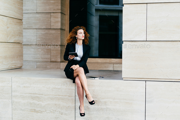 Female entrepreneur with slender legs, wearing black formal costume ...