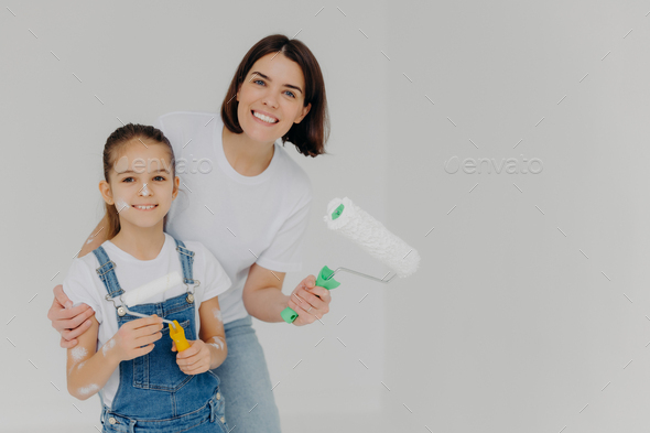 Positive caring mother cuddles child, have fun when refurbish walls ...