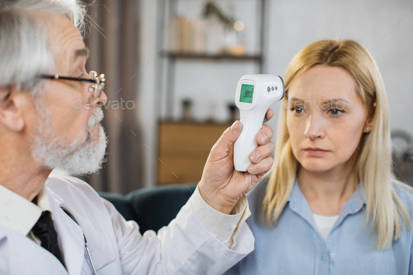 Doctor hand measuring body temperature of lady patient using infrared ...