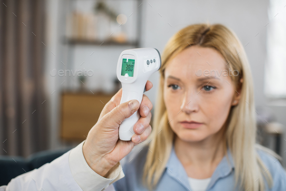 Doctor hand measuring body temperature of lady patient using infrared ...