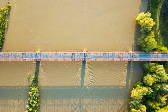 Aerial view of a narrow road bridge stretching over muddy wide river in ...
