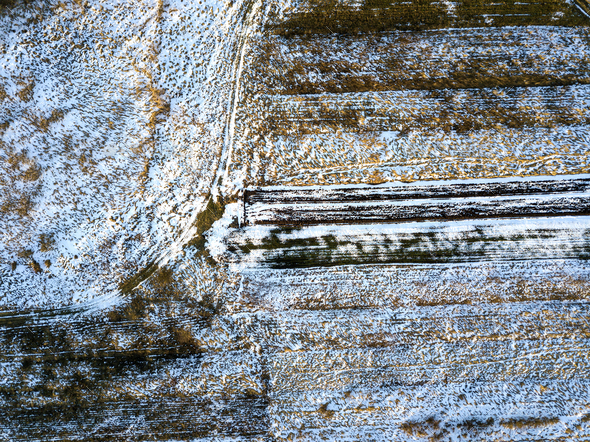 Top view of empty snowy and dark fields patched landscape on sunny ...