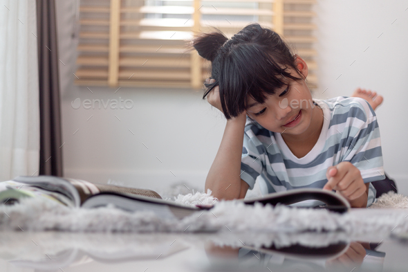 Child reading book at home. Girl lying and reading indoors Stock Photo ...