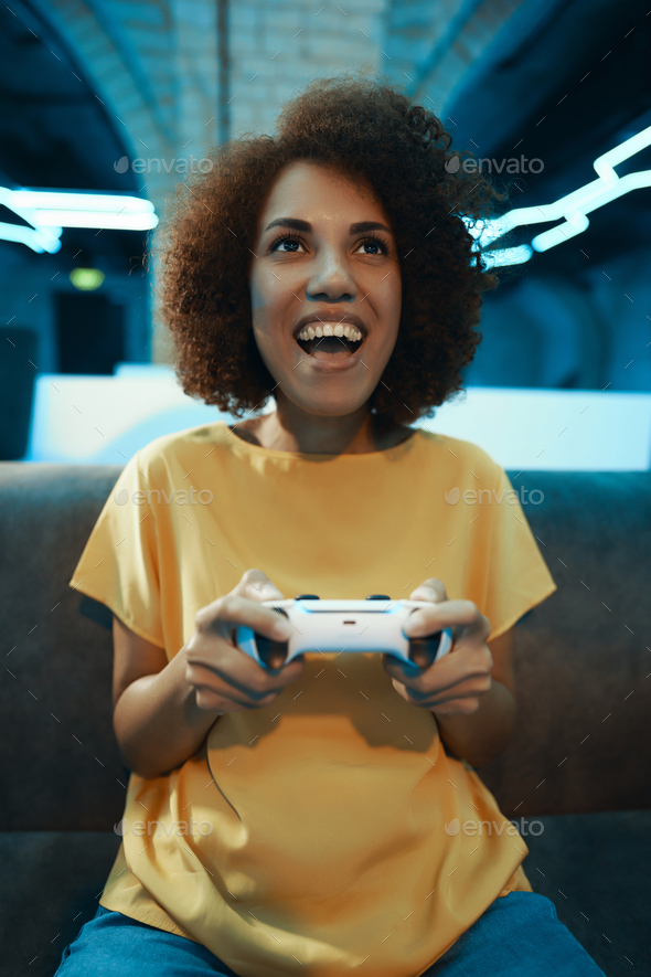 A young woman plays on a console. The emotion of victory, excitement ...