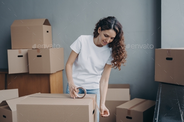 Delivery service female worker using duct tape packing goods in ...
