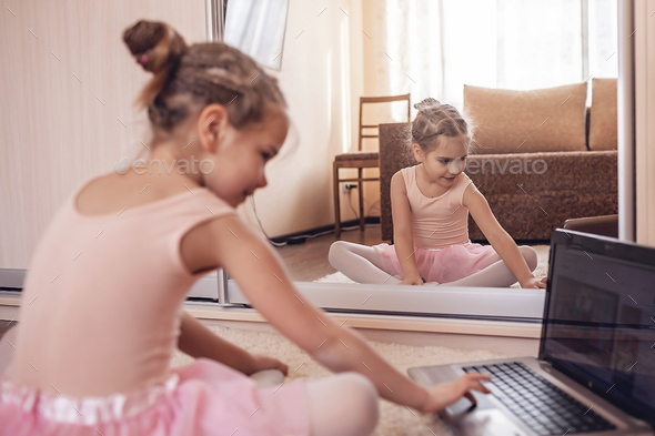 Young ballerina practicing classic choreography during online class in ...