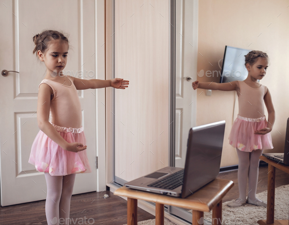 Young ballerina practicing classic choreography during online class in ...