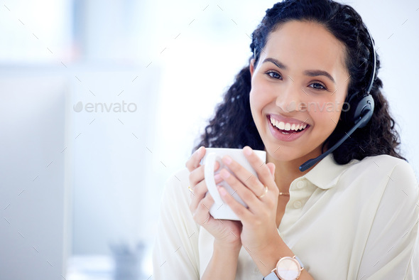 Portrait of a young call centre agent drinking coffee while working in ...
