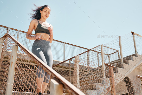Shot of an attractive young woman running down stairs during her ...