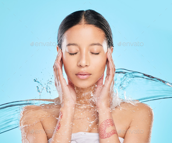 Shot of a beautiful young woman being splashed with water against a ...