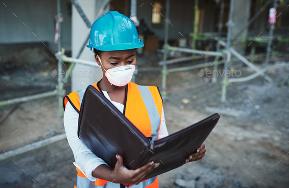Plan well, build well. Shot of a young woman going over building plans ...