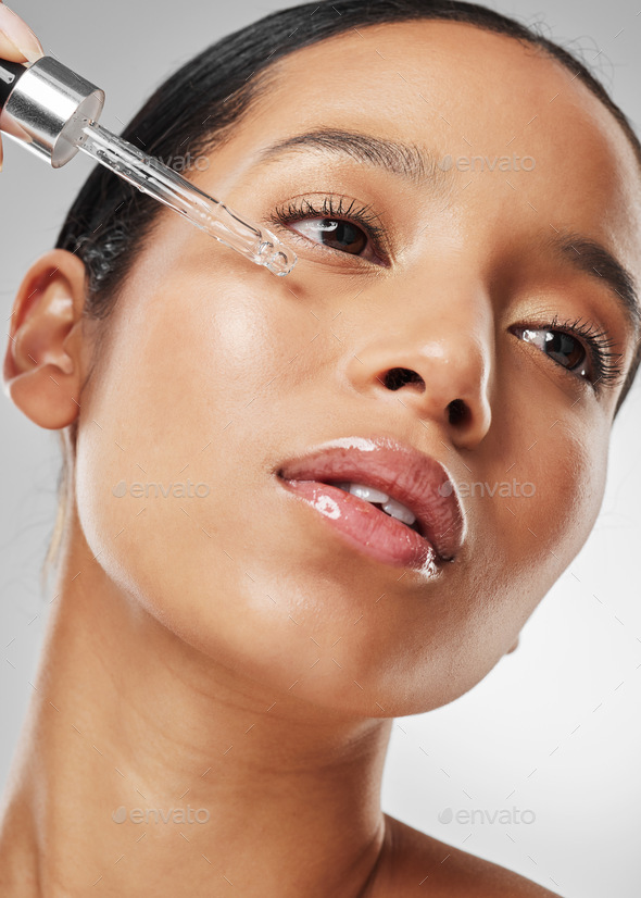 Studio shot of an attractive young woman applying serum to her face ...