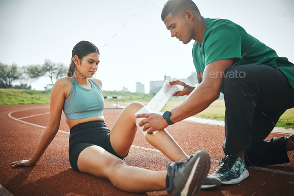 Shot of a sports paramedic providing first aid to an athlete on a ...