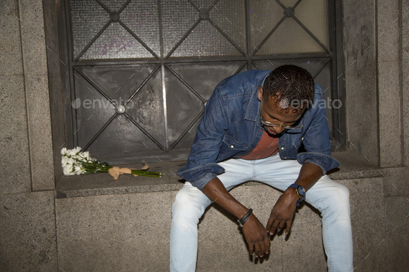 Sad man sitting in the street beside a bouquet of flowers Stock Photo ...