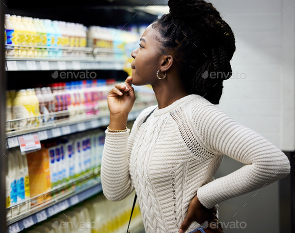 Shot of a young woman browsing through the offerings in the fridge of ...