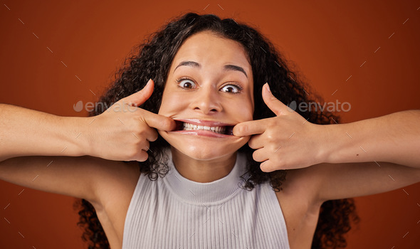 Cropped portrait of an attractive young woman making a face in studio ...