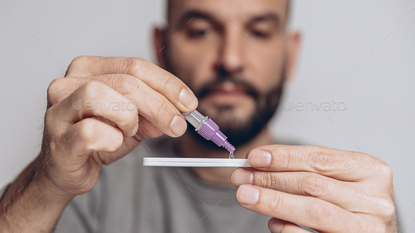 Man holds covid antigen test while releasing drop of liquid on test on ...