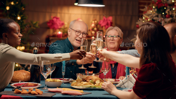 Positive festive people celebrating Christmas at evening dinner while ...