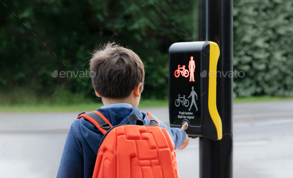 Rear view portrait kid pressing button at traffic lights on pedestrian ...