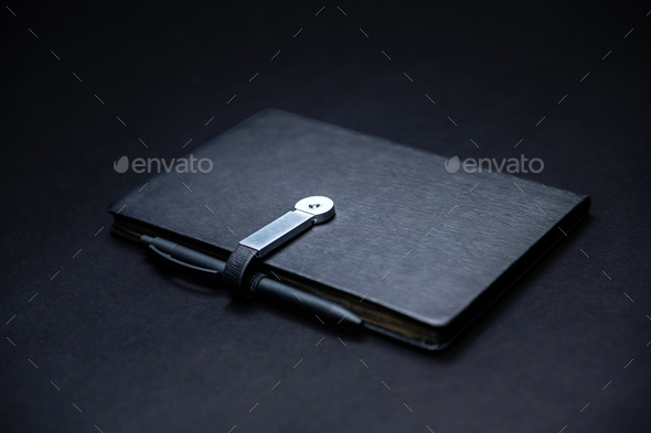black planner or notebook with pen isolated on black background, mockup ...