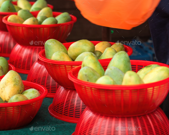 Fresh mangoes in red baskets at the stall. Stock Photo by ellinnur