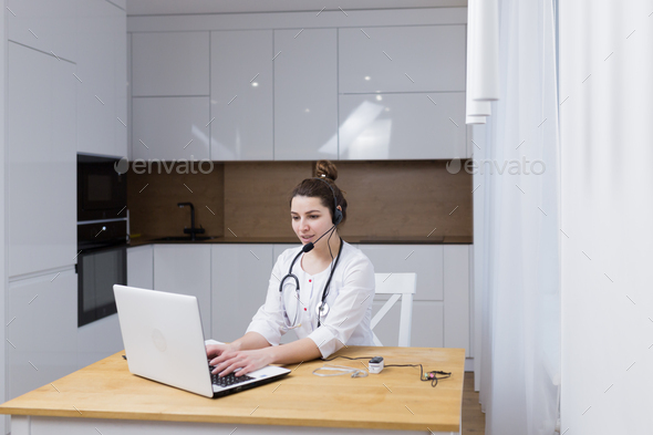 Portrait of a young female doctor student taking an exam online with a ...