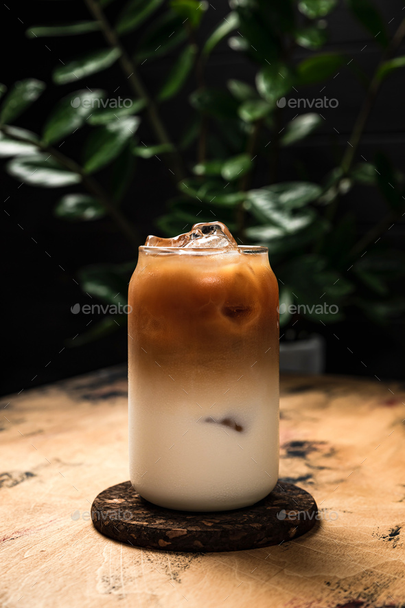 Cold iced latte coffee. A tall highball glass filled with ice cubes, layered refreshing drink ...