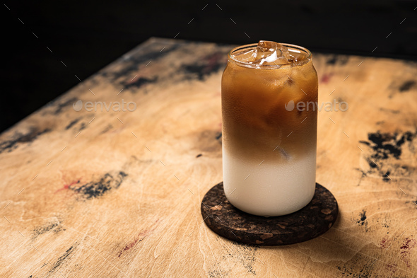 Cold iced latte coffee. A tall highball glass filled with ice cubes, layered refreshing drink ...