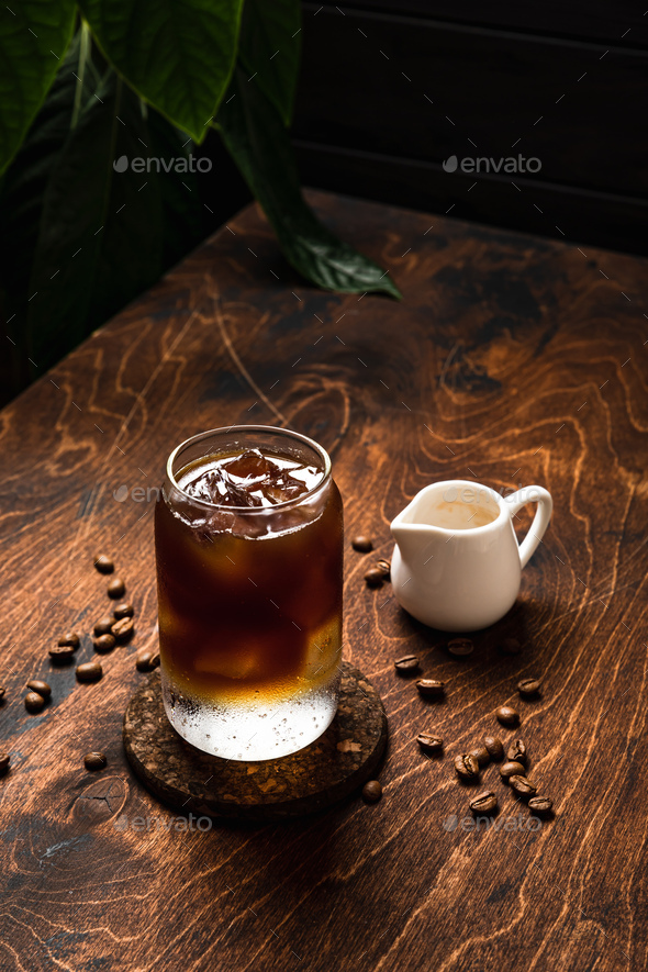 Cold espresso tonic. A highball glass filled with ice cubes, tonic soda water, coffee beans ...