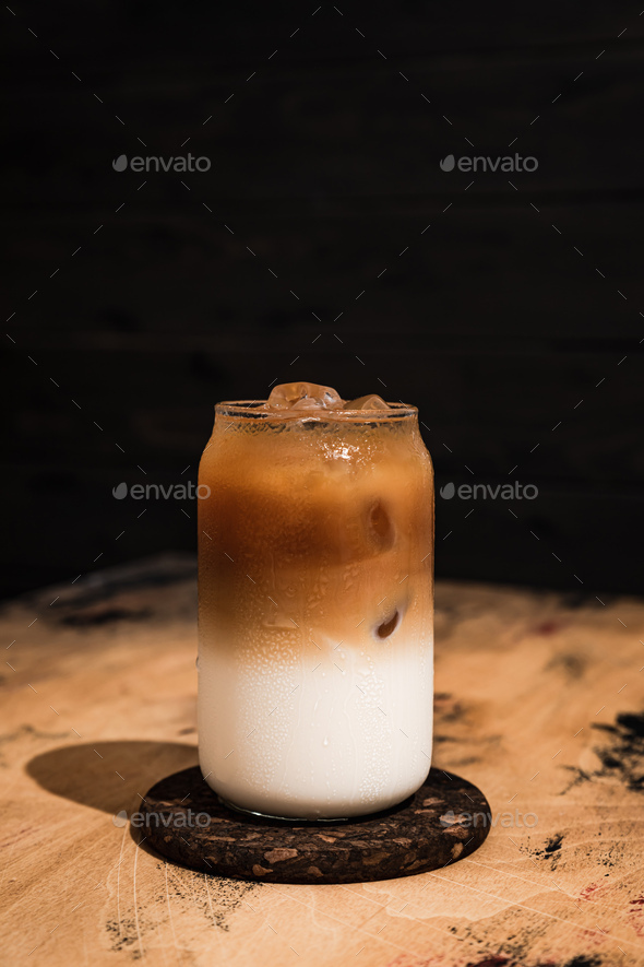 Cold iced latte coffee. A tall highball glass filled with ice cubes, layered refreshing drink ...