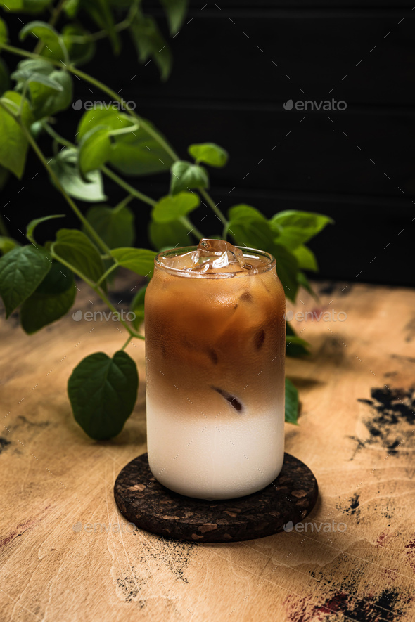Cold iced latte coffee. A tall highball glass filled with ice cubes, layered refreshing drink ...